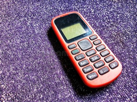 Old Mobile Phone With Texting Or Sms Button Keyboard Or Keypad On Sparkling Purple Fabric