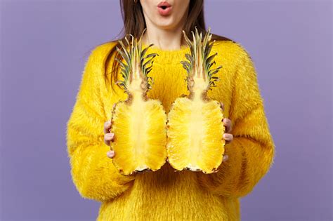 보라색 파스텔 벽 배경에 고립 된 신선한 잘 익은 파인애플 과일의 Halfs를 들고 모피 스웨터에 젊은 여자의 자른 이미지 사람들은 생생한 라이프 스타일 휴식 휴가