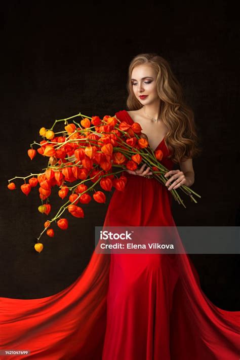 검은 색 배경에 마른 오렌지색 대변 꽃다발이있는 빨간 드레스에 긴 금발 머리를 가진 젊은 모델의 스튜디오 사진 시리즈 롱드레스에 대한 스톡 사진 및 기타 이미지 Istock