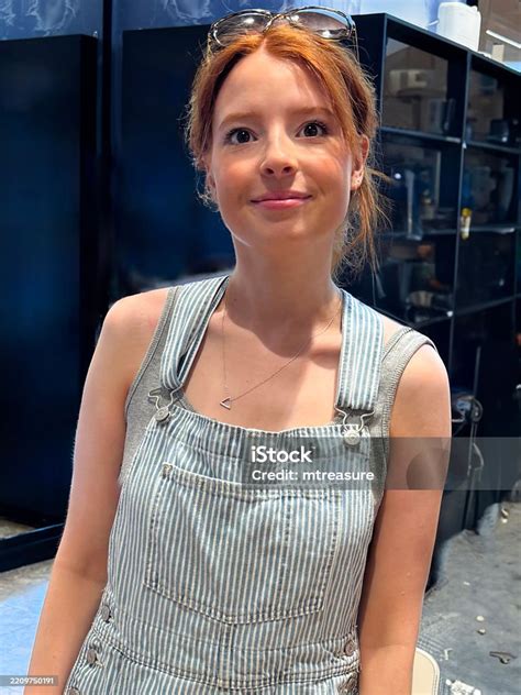 알아볼 수 없는 빨간 머리의 여성이 머리 위에 선글라스를 끼고 바깥에 서서 탈의실에서 파란색과 흰색 줄무늬 데님 짧은 바지를 입어보고 백화점 탈의실 정면도 전경에 초점을