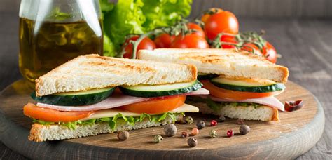 클럽 샌드위치의 클로즈업 사진 고기 프로슈토 살라미 샐러드 야채 양상추 토마토 양파 겨자를 나무 배경에 신선한 슬라이스 호밀 빵에 샌드위치 올리브 배경입니다 0명에 대한