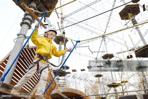 어린 소년은 어린이 아모웅 로프 계단 다리를 위한 어드벤처 파크에서 즐거운 시간을 보내고 있습니다 공공 공원에서 야외 등반 모험 놀이터 아이들을위한 활동 엔터테인먼트 공원에