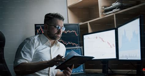 집중된 심각한 성인 기업가 흰 셔츠를 입은 수염 난 남자는 인덱스 차트에 여러 컴퓨터 화면이 있는 사무실에서 일합니다 사진 Unsplash의 전문 직업 이미지