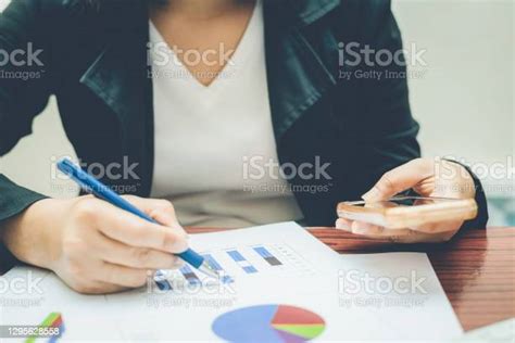 스마트 폰 기술을 사용하는 비즈니스 우먼 손은 종이 작업에 성장 통계 차트와 그래프를 가리키는 사용 펜으로 분석 및 예산 재무