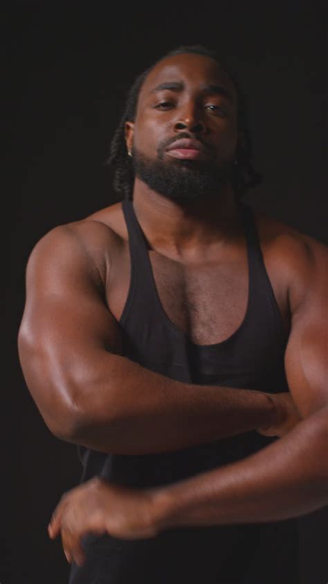 무료 스톡 영상 검은색 스튜디오 배경에 대한 스포츠 이벤트 훈련을 위해 카메라를 향해 고 초점을 맞추는 근육 체형의 피트니스 베스트를 입은 심각한 남성 운동 선수의 수직