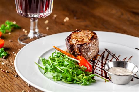 조지아 요리입니다 수 분이 많은 쇠고기 스테이크 송아지 스테이크 구이 로켓 구운된 야채와 소스와 함께 흰색 접시에 테이블에 붉은