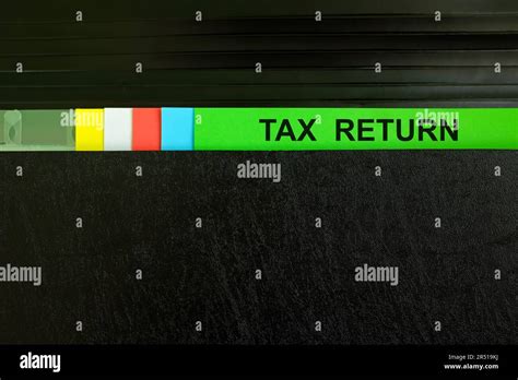 Hand Picking Tax Return File Record In Black Binder Folder Filing Accounting And Taxation