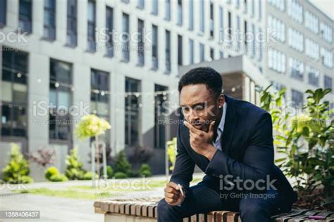 도시 거리 배경에 도시 공원 벤치에 앉아 야외에서 대마초를 흡연 아프리카 계 미국인 사업가 남성 직원 사업가 양복을 입은 사무실 노동자는 외부 마리화나를 스트레스를 완화