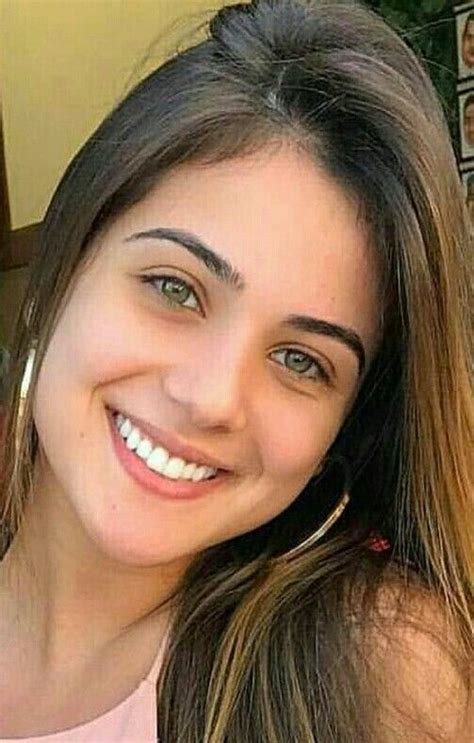 A Woman With Long Brown Hair Smiling At The Camera And Wearing Hoop Earrings On Her Head