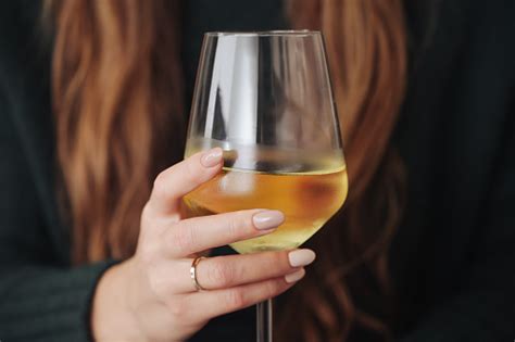 와인을 마시는 여자 화이트 와인 마시기 손에 와인 잔 모직 스웨터를 입은 소녀 아늑한 겨울 알코올 배경입니다 와인 잔을 들고 있는 여성의 손입니다 개념에 대한 스톡 사진 및