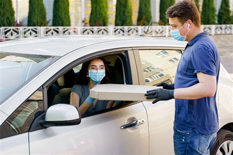 젊은 백인 학생은 배달 회사에서 검역 코로나 바이러스에서 식품 택배로 일합니다 편리하고 안전자동차로 배송 골판지 상자에 최고의