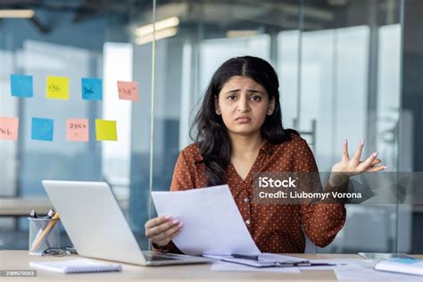라틴 아메리카 여성 사업가는 노트북과 스티커 메모가있는 사무실 환경에서 문서를 작업하면서 혼란스러워합니다 결정에 대한 스톡 사진 및 기타 이미지 Istock