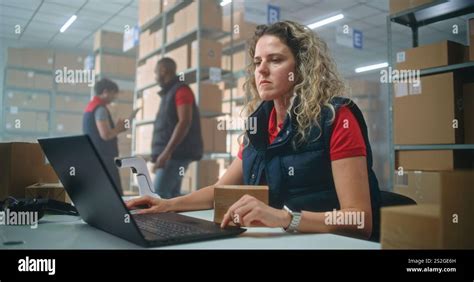 Female Logistics Specialist Scans Parcel With Barcode Scanner Checks Data Using Laptop Sorting