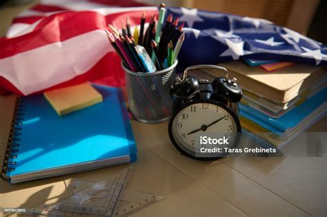 검은 색 알람 시계 학용품 문구류 및 미국 국기가있는 테이블에 쌓인 교과서를 배경으로 삼습니다 0명에 대한 스톡 사진 및 기타 이미지 Istock