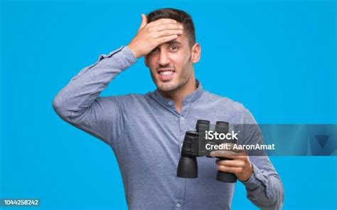 잘생긴 젊은 남자 머리에 손으로 압박 하는 쌍안경을 통해 보고 충격 수치심과 깜짝 얼굴로 분노와 좌절 두려워 하 고 실수에 대 한 화가 감정에 대한 스톡 사진 및 기타