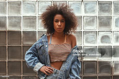 그녀는 모두 패션에 관한 것입니다 자신감 아프리카 미국 청바지 재킷 여자 엉덩이에 손을 유지 하 고 카메라를 보고 재킷에 대한