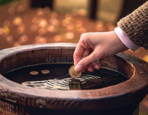 A Hand Flicking A Coin Into A Wishing Well Capturing A Moment Of Hope