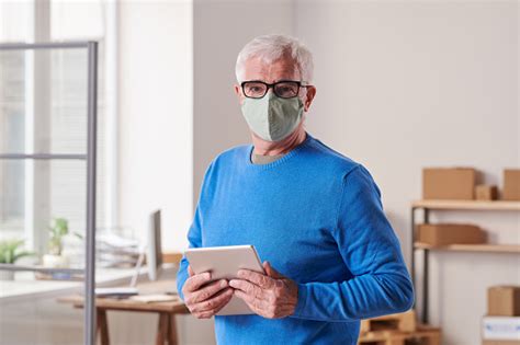 작은 창고에서 디지털 태블릿을 들고 천 마스크와 파란색 스웨터에 선임 노동자의 초상화 65 69세에 대한 스톡 사진 및 기타 이미지 65 69세 경영자 남자 Istock