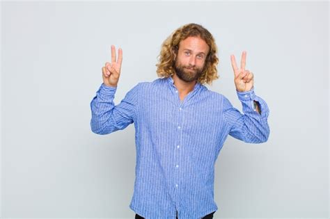 Hombre Rubio Sonriendo Y Mirando Feliz Amigable Y Satisfecho Gesticulando Victoria O Paz Con