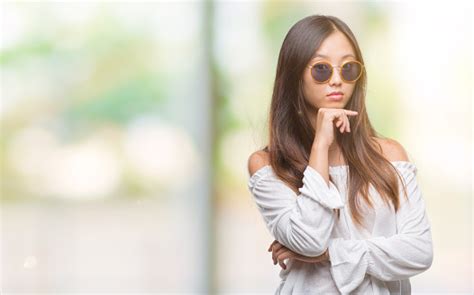 젊은 아시아 여자 손으로 턱 질문 잠겨있는 표현에 대 한 생각에 고립 된 배경 위에 선글라스를 착용 사려깊은 얼굴 미소 의심 개념입니다 긴 머리에 대한 스톡 사진 및 기타