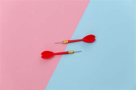 분홍색 파란색 파스텔 배경에 금속 팁이있는 두 개의 빨간 플라스틱 다트 맨 위 보기입니다 플랫 레이 미니멀리즘 겨냥에 대한 스톡 사진 및 기타 이미지 Istock
