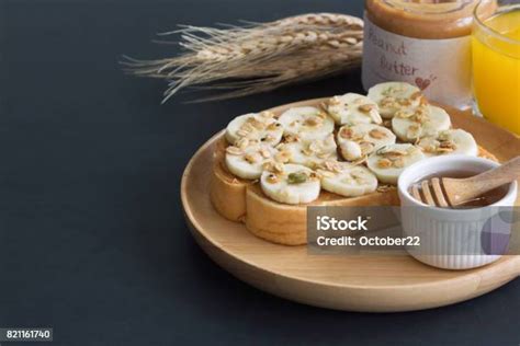 꿀 나무 접시에 바나나 땅콩 버터 토스트 샌드위치 홈메이드 오픈 샌드위치 바나나 슬라이스 및 그 라 놀라와 위에 땅콩 버터를