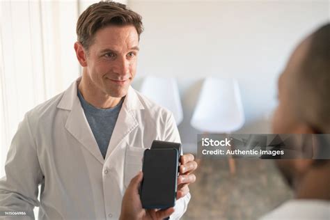 흑인 환자를 위해 신용 카드 판독기를 들고 의사 사무실에서 스마트 폰으로 비접촉식 지불을하는 남성 관리자 비접촉 결제에 대한 스톡 사진 및 기타 이미지 Istock