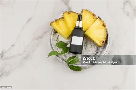 파이펫이 달린 검은 무광택 화장품 병은 파인애플 슬라이스와 석고 접시에 놓여 있습니다 맨 위 보기입니다 대리석 배경 브랜드가 없는 목압 뷰티 스파에 대한 스톡 사진 및 기타