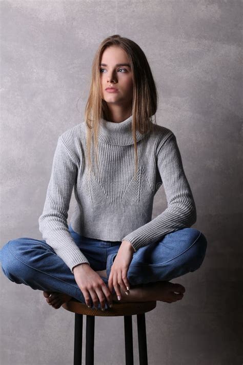 Девушка в свитере сидя на стуле бара Серая предпосылка Стоковое Фото изображение насчитывающей