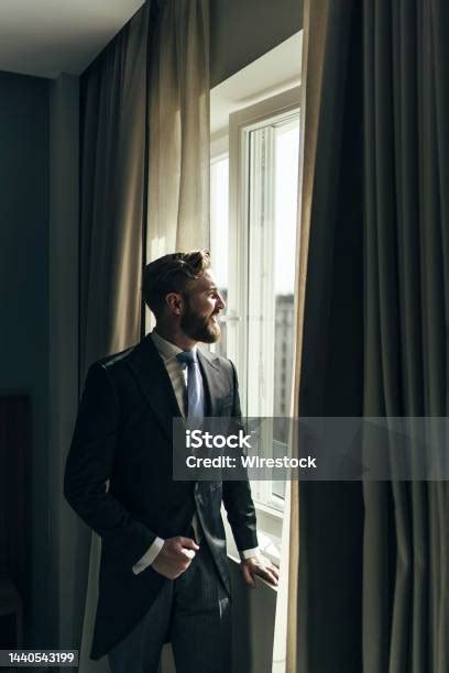 우아한 양복을 입고 창문 근처에 서 있는 수염을 가진 성인 남성의 얕은 초점 명랑한에 대한 스톡 사진 및 기타 이미지 명랑한 사람들 사진 이미지 Istock