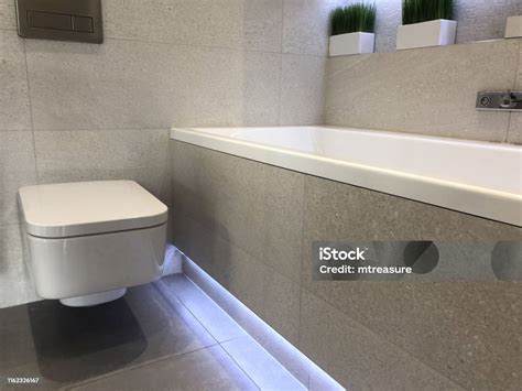 현대 광장 벽 매달려 화장실 팬 화장실 벽에 걸려 현대 흰색 럭셔리 욕실 스위트의 이미지 큰 베이지 색 돌 화강암 벽 타일과 타일 바닥 욕조 주각 방수 Led 조명과 탭싱크