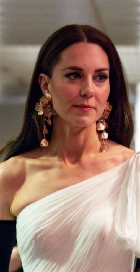 A Woman In A White Dress With Large Gold Earrings On Her Left Shoulder