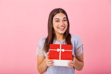 분홍색 배경에 빨간 크리스마스 선물 상자를 손에 들고 있는 쾌활한 잘 생긴 젊은 여성 컨셉 홀리데이 및 선물 20 24세에 대한 스톡 사진 및 기타 이미지 Istock