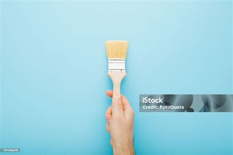 젊은 성인 남자 손 들고 새로운 페인트 브러시 에 밝은 파란색 테이블 배경 파스텔 색상 근접 촬영 가정의 수리 작업을 위한 준비