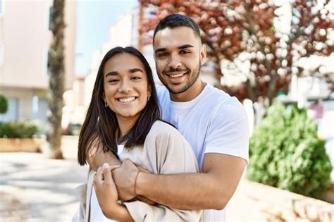 Joven pareja latina sonriendo feliz y abrazándose en la ciudad Foto Premium
