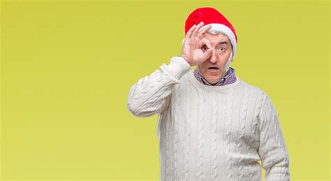 놀란된 얼굴 손가락을 통해 보고 눈으로 확인 제스처를 하 고 격리 된 배경 위에 크리스마스 모자를 쓰고 잘생긴 수석 남자 충격