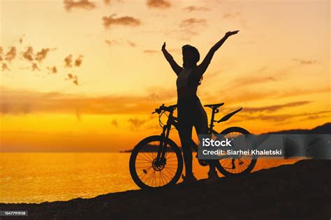 활동적인 한 명의 무료 행복 즐거운 평온한 영감을 받은 여성 자전거 타는 사람의 실루엣은 일몰 하늘을 배경으로 야외에서 자전거와