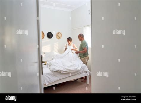 Couple Making Bed In Bedroom Stock Photo Alamy