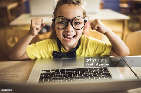 Happy Nerdy Schoolgirl Celebrating Her Success While Using Laptop On A