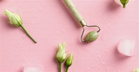 Gua Sha 옥 돌 얼굴 롤러 얼음 조각 분홍색 배경에 봄 꽃 얼굴 피부 치료 개념입니다 플랫 레이 평면도 사진 Unsplash의 유행 이미지