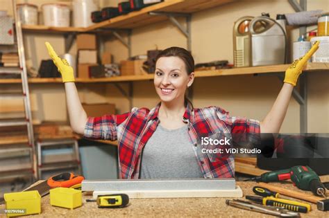 격자 무늬 셔츠 회색 티셔츠에에서 아름 다운 백인 젊은 갈색 머리 여자 손 나무 테이블에서 목공 워크숍에서 작업을 확산 하는 노란색 장갑 철 조각과 나무 다른 도구와 장소