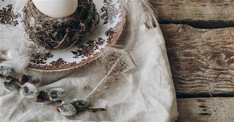 세련된 소박한 부활절 테이블 세팅 빈티지 접시 린넨 냅킨 오래된 나무에 음부 버드 나무 가지에 부드러운 깃털이 있는 둥지에 자연 부활절 달걀 시골 부활절 정물