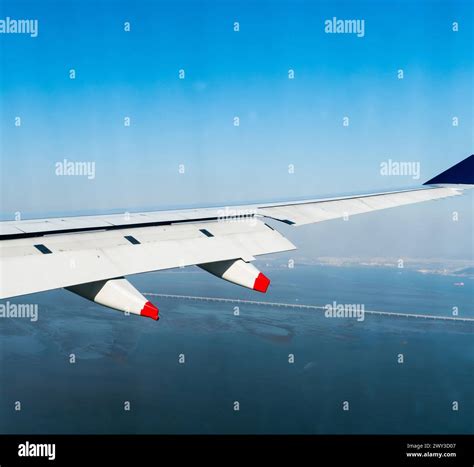 Aircraft Wing With Red Tipped Pillion In Flight Above Ocean Coastline