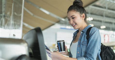 스마트폰 응용 프로그램을 사용하여 웃는 아시아 여성의 쉬운 체크인 신청 카운터를 통해 비행 좌석 정보를 확인하기 위해 바코드를 스캔하십시오 공항 터미널 스마트 기술 응용