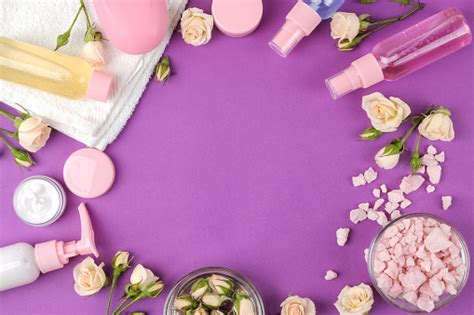 밝은 보라색 배경에 신선한 장미와 분홍색 병에 얼굴과 몸에 대한 화장품 크림과 로션 바다 소금과 비누 스파 위에서 볼 수 있습니다 텍스트 공간 0명에 대한 스톡 사진 및