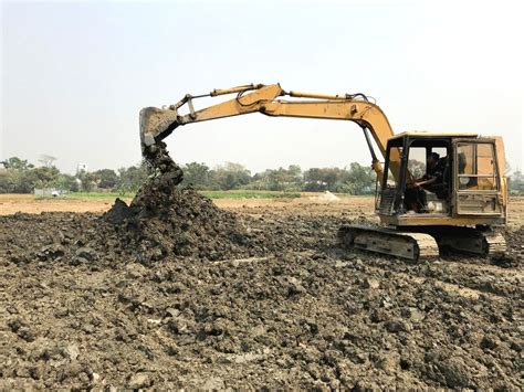 Premium Photo A Digger Digging A Field With A Man Sitting On The Back