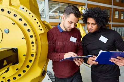 Engineers Programming Robotic Arm For Industrial Automation In Modern Facility Stock Image
