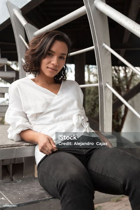 라틴어 젊은 갈색 머리 여자 곱슬 머리와 짧은 머리 앉아 휴식 에 계단 흰색 블라우스와 검은 바지를 입고 하루에 사진 20 24세에 대한 스톡 사진 및 기타 이미지 Istock