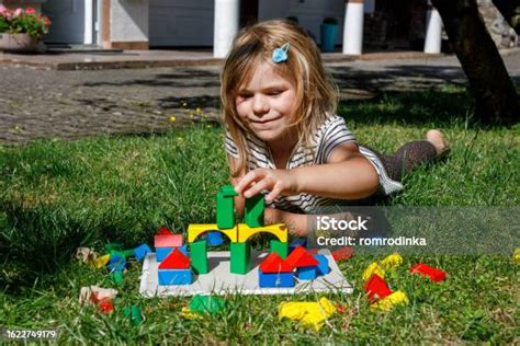 어린 미취학 아동이 야외 탁자 위에서 나무 블록을 가지고 놀고 있다 어린 아이들을 위한 교육용 게임 행복한 아이는 나무 무지개