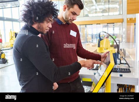 Engineers Collaborate And Train On Programming Robotic Arms Using A Touch Panel In A Modern